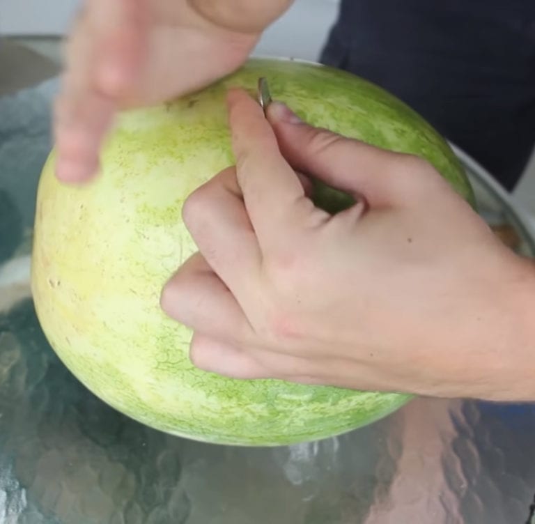 Guy demonstrates how to open up a watermelon using just a quarter