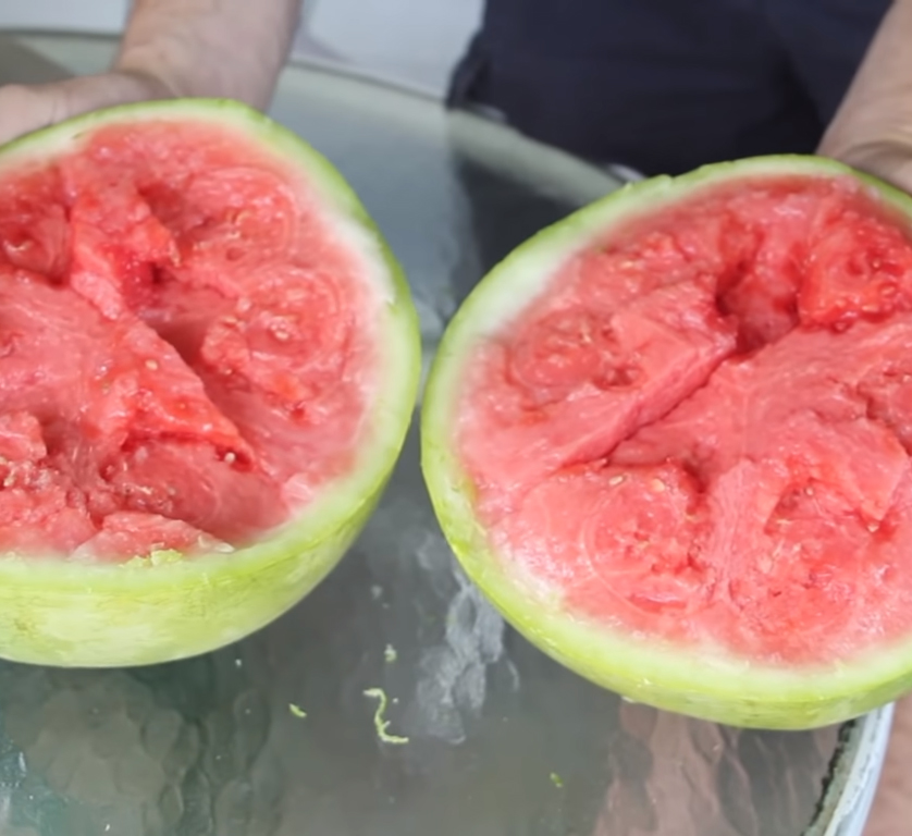 Guy demonstrates how to open up a watermelon using just a quarter
