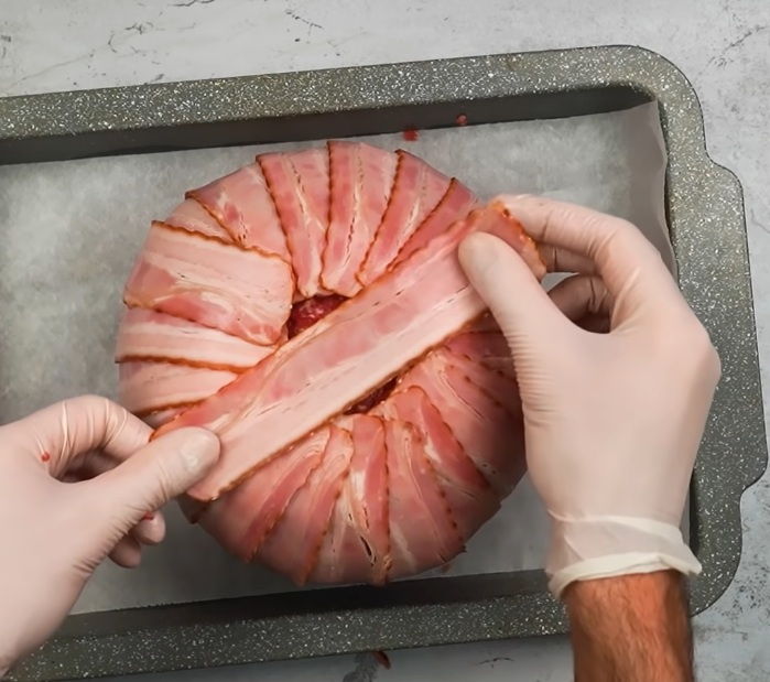 Chef wraps bacon around cabbage stuffed with cheese and ground beef for ...