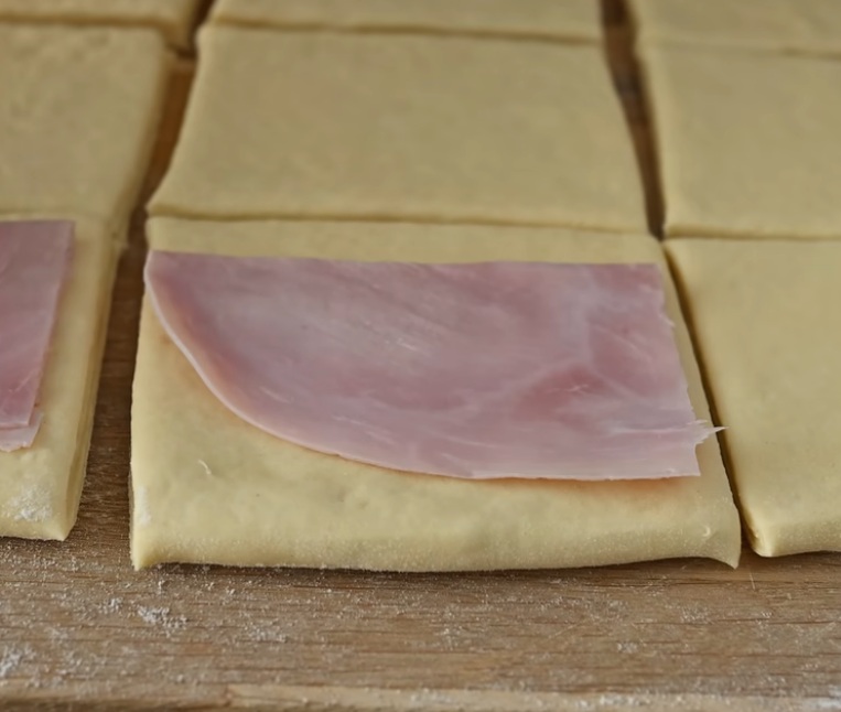 Add cheese and ham between sheets of buttered dough and top with egg ...