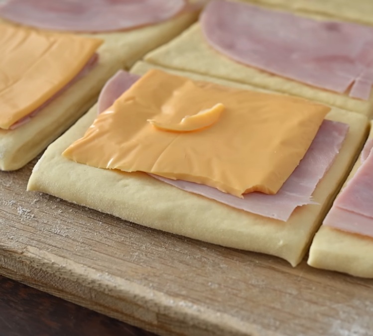 Add cheese and ham between sheets of buttered dough and top with egg ...
