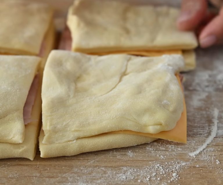 Add cheese and ham between sheets of buttered dough and top with egg ...