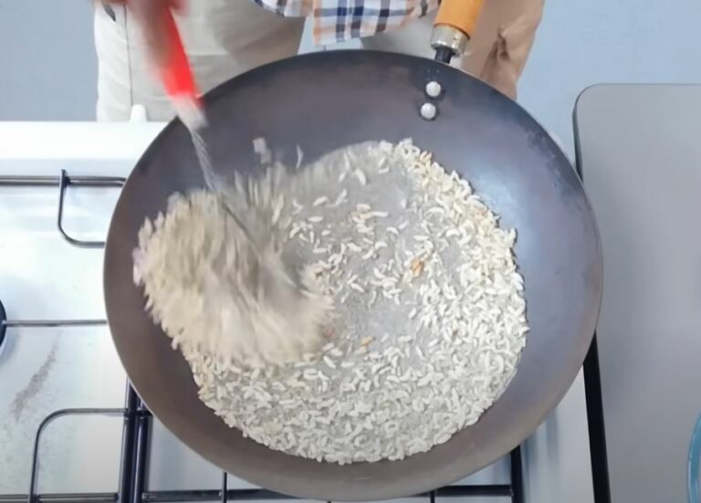 Teacher pours rice into a frying pan with salt to show how to make ...