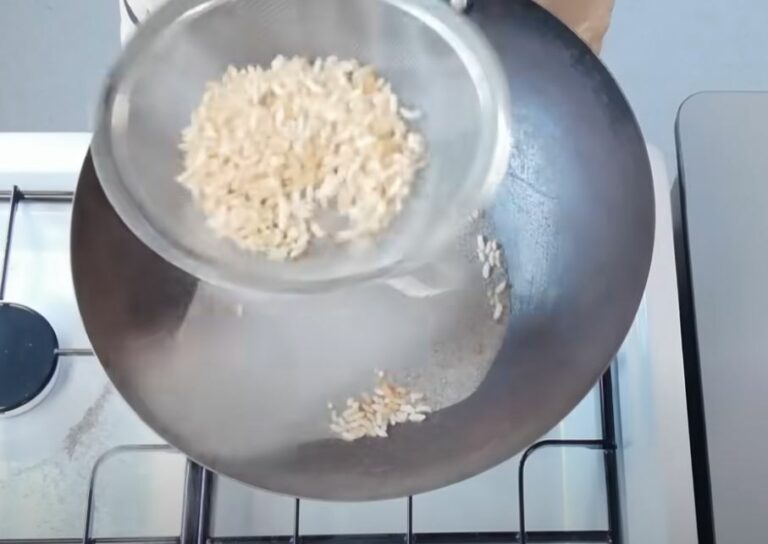 Teacher pours rice into a frying pan with salt to show how to make ...