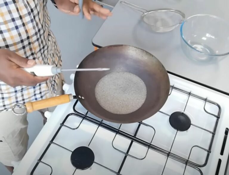 Teacher pours rice into a frying pan with salt to show how to make ...